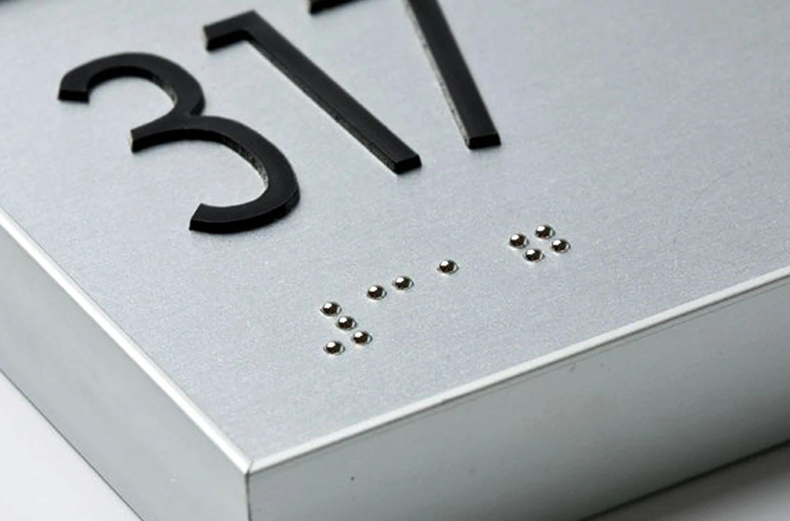 Close-up of a room number sign featuring raised black numbers and ...